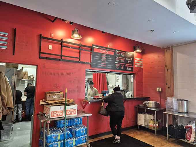 Step inside where red walls and industrial lighting create the perfect backdrop for serious sandwich construction.