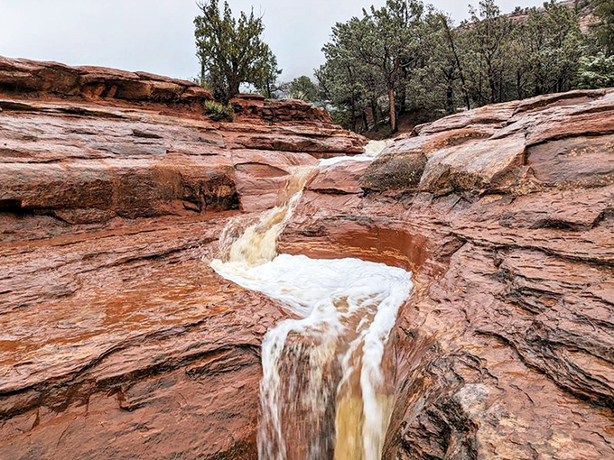 Water cascades over red rock ledges after a desert rain, transforming Sedona's typically dry landscape into a momentary oasis of flowing beauty.