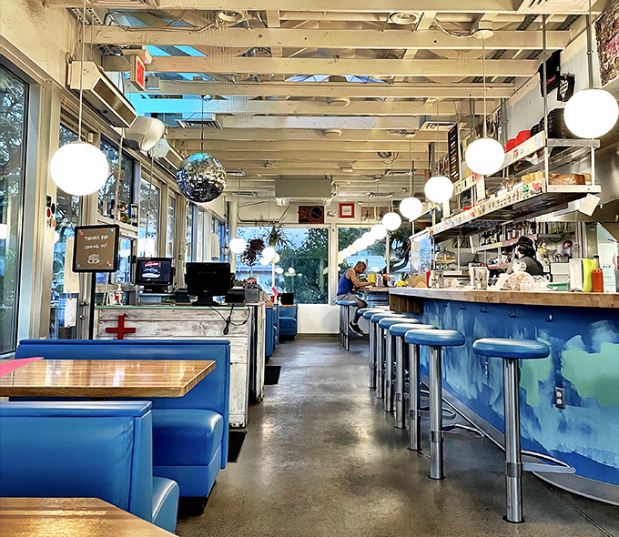 Blue booths and counter seating create a retro-modern vibe where nostalgia meets contemporary comfort &ndash; no Instagram filter needed.