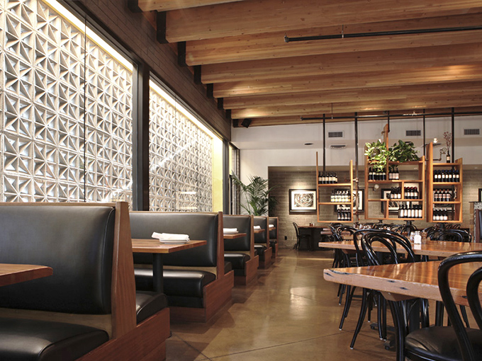 Warm wood meets cool concrete inside The Parlor, where geometric screens filter Arizona sunshine into artistic patterns across comfortable leather booths.