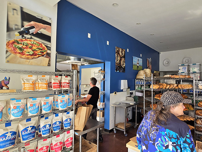 Inside the bakery, vibrant blue walls provide the perfect backdrop for racks of golden loaves, where bread becomes both sustenance and art.