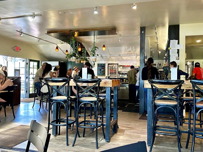 Inside, rustic elegance meets casual comfort with blue bistro chairs and hanging plants creating an atmosphere that feels both special and homey.