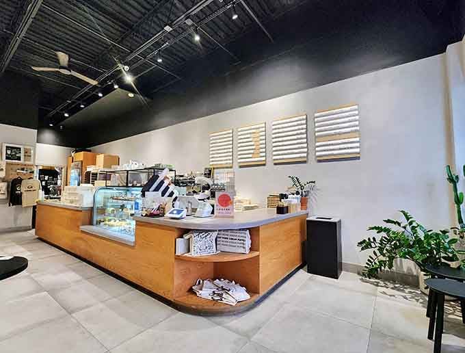 Plants cascade from shelves while natural light bathes the minimalist interior, creating the perfect backdrop for your inevitable sugar-induced euphoria.