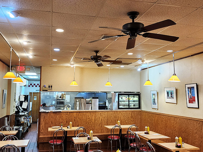 Simple wooden paneling and yellow pendant lights create that perfect old-school deli atmosphere where comfort trumps trendiness every time.