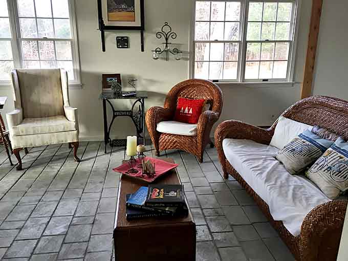 Sunlight streams through windows in this cozy sunroom, where wicker furniture and casual elegance invite you to linger with a good book.