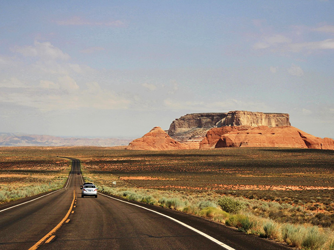 LeChee Rock stands sentinel over the highway, its massive silhouette a dramatic punctuation mark against the endless blue Arizona sky.