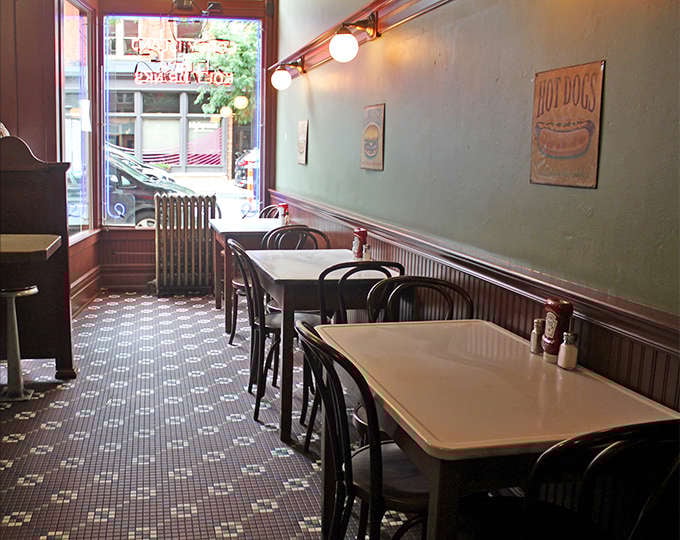 Simple tables, classic bentwood chairs, and mint-green walls create an unpretentious dining space where conversations flow as freely as the coffee refills.