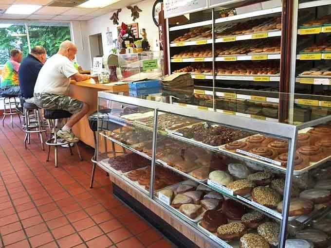 Morning regulars perch at the counter, participating in the daily ritual of donut diplomacy while display cases showcase edible artwork waiting for their forever homes.
