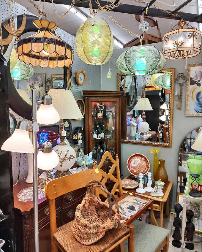 Vintage lighting creates pools of amber warmth throughout the store, with Tiffany-style shades casting colorful patterns that dance across antique furnishings.