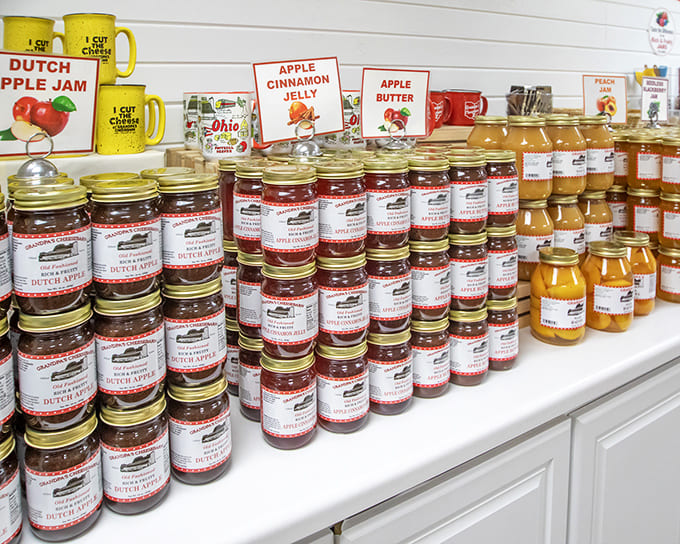 Jars of Dutch Apple Jam and Apple Butter stand in neat rows, their contents glowing amber and ruby in the light like edible gemstones.