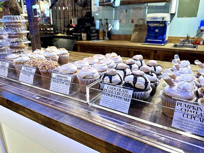 A lineup of frosted perfection awaits behind glass, each cupcake standing at attention like delicious little soldiers ready for duty.