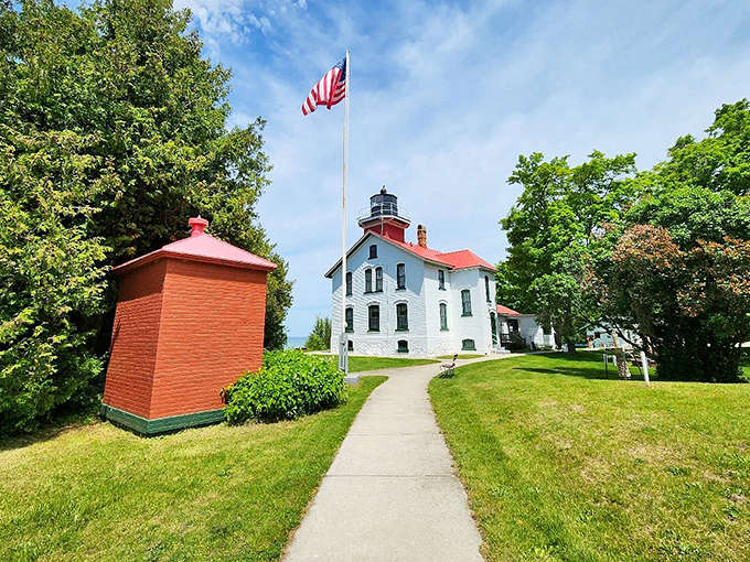 Old Glory waves proudly beside the historic lighthouse, a reminder of the structure's service to American maritime commerce and safety.