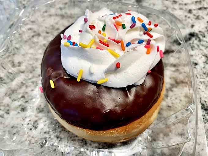 This chocolate-dipped beauty topped with whipped cream and rainbow sprinkles isn't just a donut &ndash; it's edible optimism with a hole in the middle.