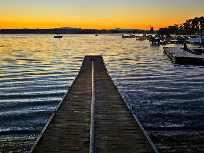 Sunset transforms Lake Champlain into liquid gold, with wooden docks stretching toward the horizon like pathways to paradise.