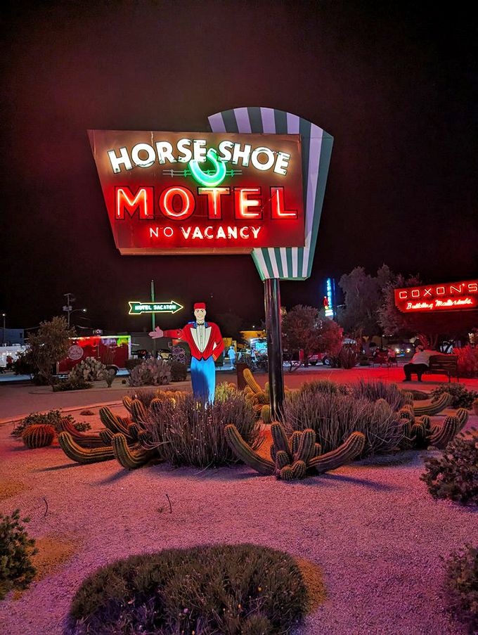 The Horse Shoe Motel sign shines brightest after dark, its distinctive green stripes and lucky horseshoe beckoning weary travelers with promises of rest and good fortune.