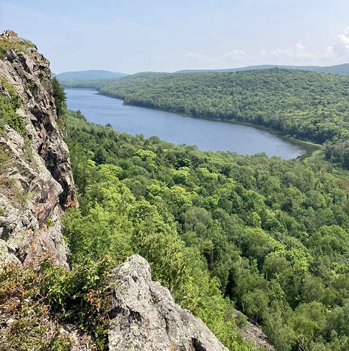 Dramatic cliffs offer vertigo-inducing views across the valley, where Lake Superior's waters meet Michigan's rugged wilderness in a breathtaking panorama.