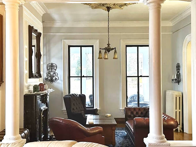 Leather chairs and classic columns frame this living room where modern comfort meets Victorian splendor – Netflix and chilling, 19th century style.