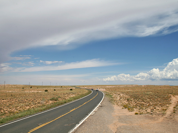 Nature's ceiling stretches infinitely above the desert floor, where puffy clouds cast playful shadows across the landscape.