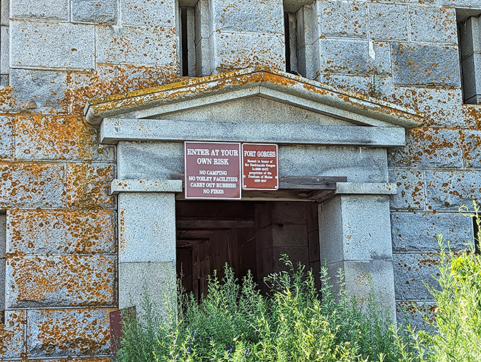 A weathered sign warns visitors to enter at their own risk, adding a touch of adventure to this abandoned military outpost.