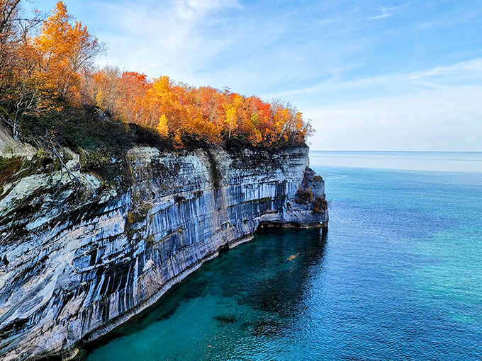 Fall transforms Pictured Rocks into nature's color palette, with autumn foliage creating a fiery crown above the ancient sandstone cliffs.