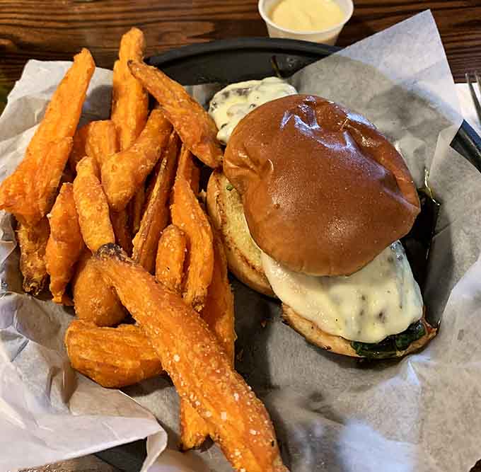 Golden sweet potato fries steal the show alongside a perfectly melted burger that demands your immediate attention.