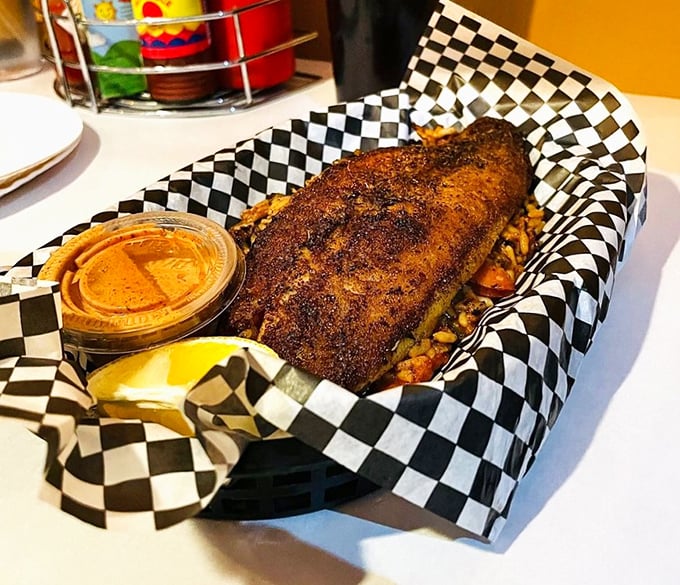 Blackened perfection on a checkered throne &ndash; this catfish wears its seasoned crust like a badge of honor.