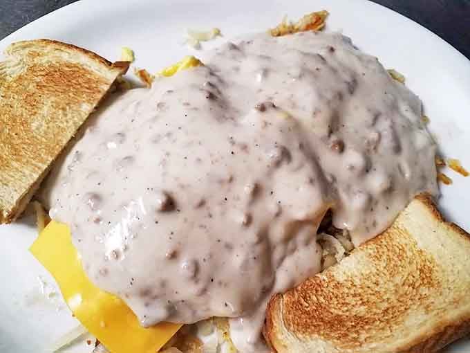 Behold the masterpiece &ndash; golden hash browns blanketed with cheese and smothered in sausage gravy that cascades like a delicious waterfall.