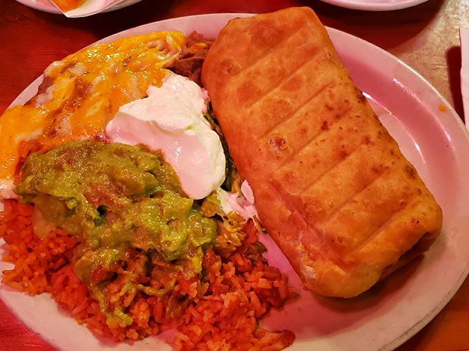 A perfect chimichanga rests on its throne of Spanish rice, surrounded by creamy guacamole and sour cream &ndash; edible artwork at its finest.