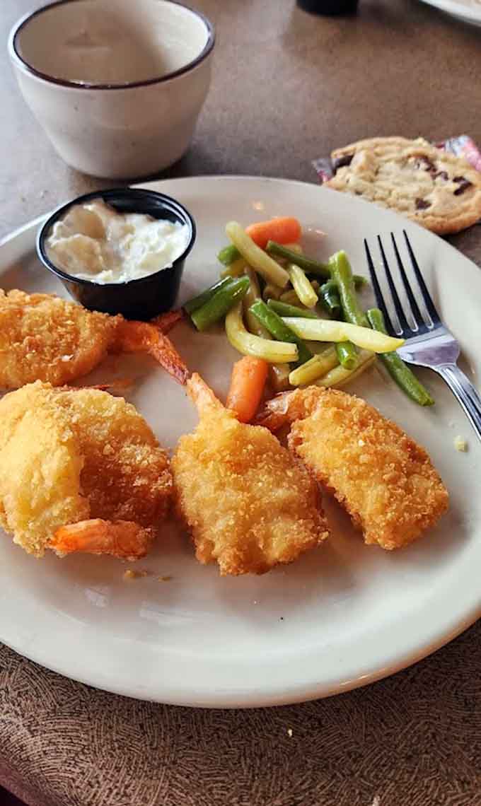 Golden-crusted jumbo shrimp arrive with vegetables and sides, proving size absolutely matters when it comes to crustaceans.