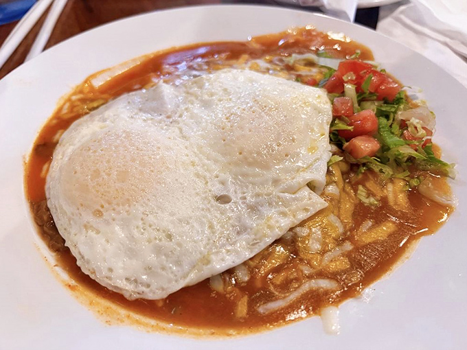 Huevos Rancheros in their purest form – sunny-side eggs atop crisp tortillas, swimming in that legendary ranchero sauce that haunts dreams.