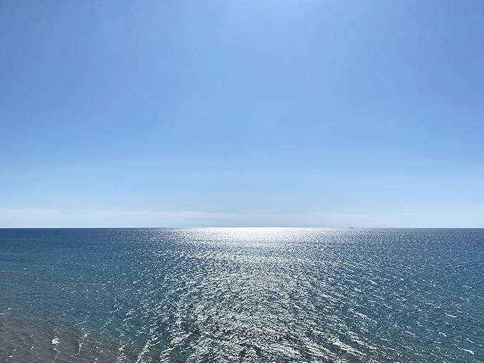 Lake Michigan stretches endlessly toward the horizon, its surface shimmering like scattered diamonds under the midday sun.