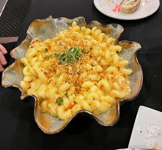 Mac and cheese transcends to heavenly heights with perfectly cooked pasta swimming in creamy cheese sauce, served in an artistic shell-shaped vessel.