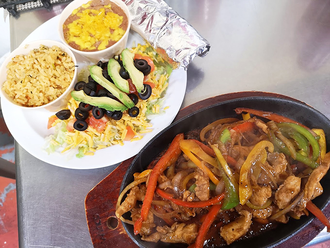 Sizzling fajitas with colorful peppers share plate space with perfectly seasoned rice and beans. That avocado isn't just garnish – it's the crowning glory.