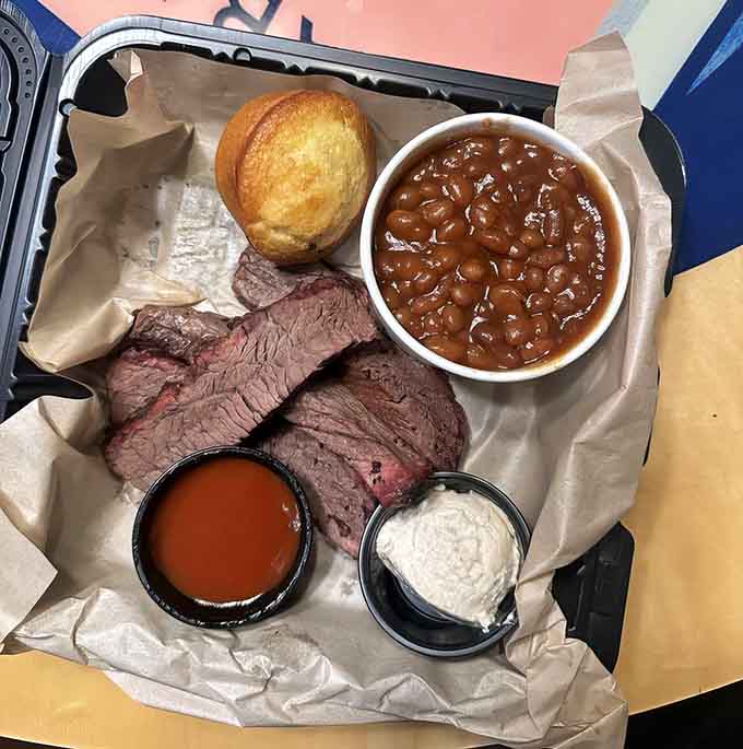 Behold the brisket plate: tender slices of hickory-smoked heaven accompanied by beans and cornbread that complete the symphony.