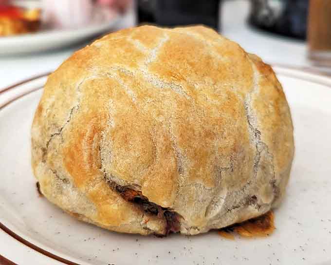 A golden-brown pasty sits majestically on its plate, a self-contained meal that miners once carried underground, now elevated to an art form.