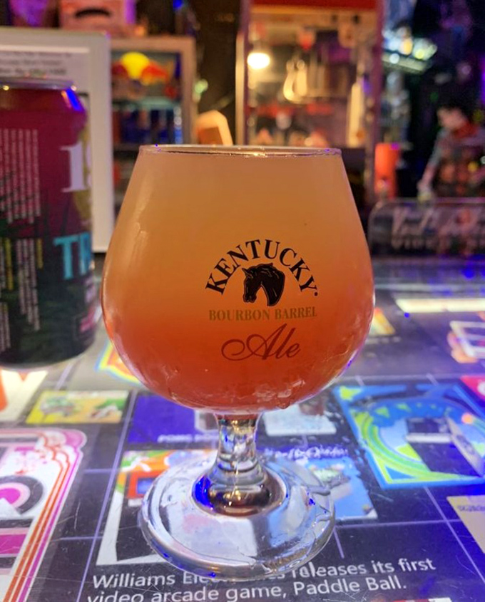 A Kentucky Bourbon Barrel Ale catches the neon glow, its amber depths promising rich flavors to complement your gaming marathon.