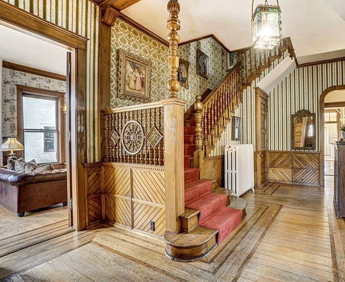 The grand staircase isn't just functional – it's architectural theater, with carved newel posts and red carpet that practically demands a dramatic entrance.