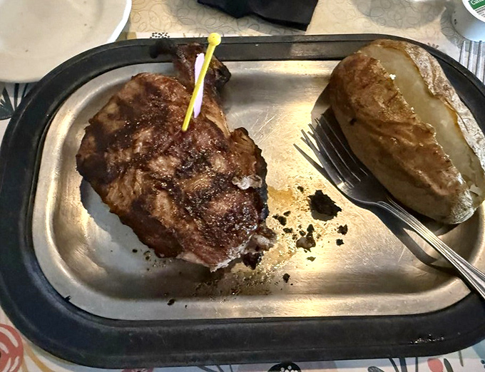 A perfectly cooked steak rests beside a golden baked potato &ndash; simplicity executed flawlessly is the hallmark of Wisconsin supper club excellence.