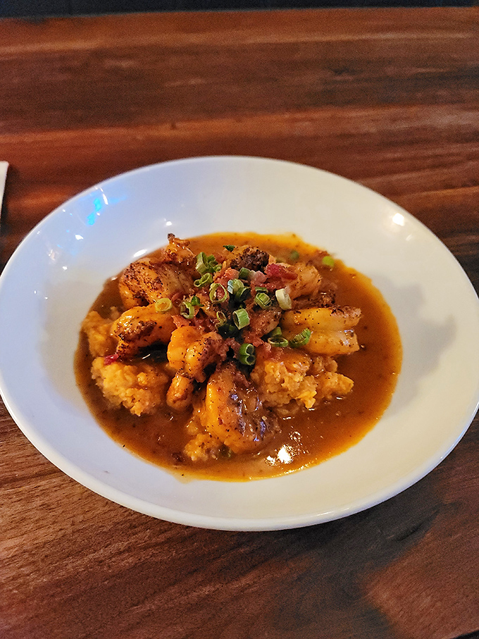 Shrimp and grits elevated to art form &ndash; plump Gulf shrimp swimming in rich broth atop creamy grits, garnished with fresh scallions.