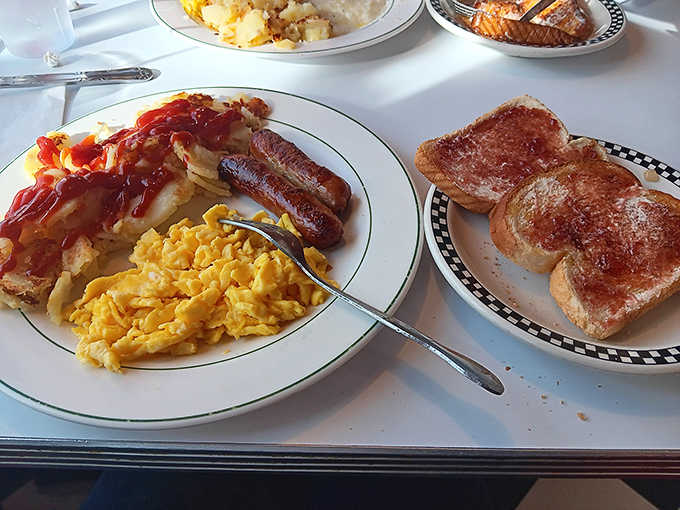 Morning glory on a plate: scrambled eggs that cloud-like, sausage with perfect snap, and toast ready for butter's embrace.