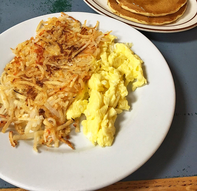 Scrambled eggs so fluffy they practically float alongside hash browns with that perfect crisp-to-tender ratio that few places ever achieve.
