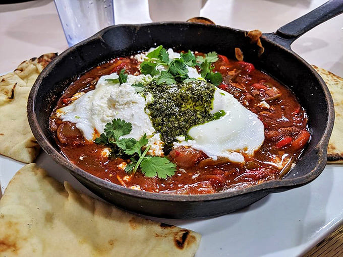 Shakshuka arrives bubbling in cast iron like a North African sunrise, with poached eggs swimming in spiced tomato sauce that'll wake up every taste bud.