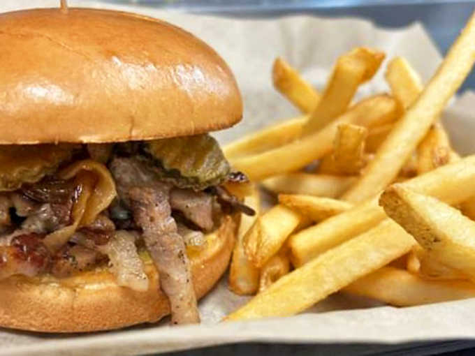 A masterpiece of simplicity – tender sliced brisket on a soft bun with golden fries that's worth driving across state lines for.