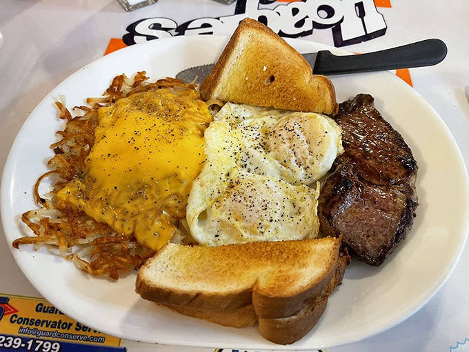 A perfect harmony of protein and comfort: steak and eggs with golden hash browns that crackle with each bite and toast ready for butter's warm embrace.