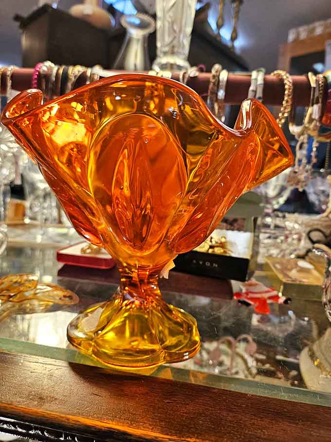The amber glass bowl catches light like liquid sunshine, its curves and folds reminiscent of a more elegant era.