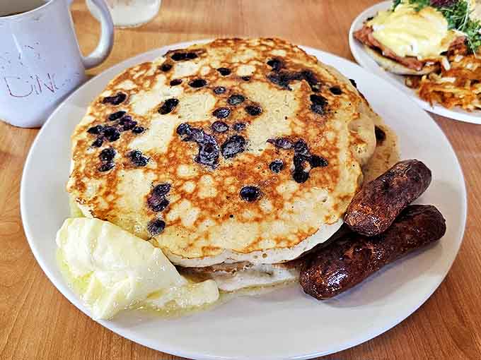 These blueberry pancakes aren't just breakfast; they're a fluffy canvas of joy dotted with bursts of fruit and accompanied by perfectly grilled sausages.
