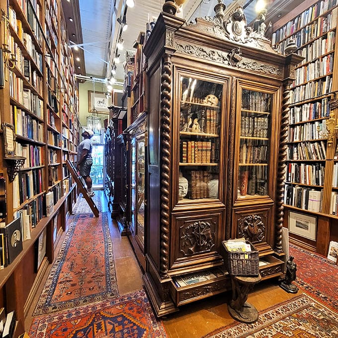 Ornate wooden cabinets with twisted columns protect rare volumes behind glass, standing sentinel over literary treasures collected across decades.