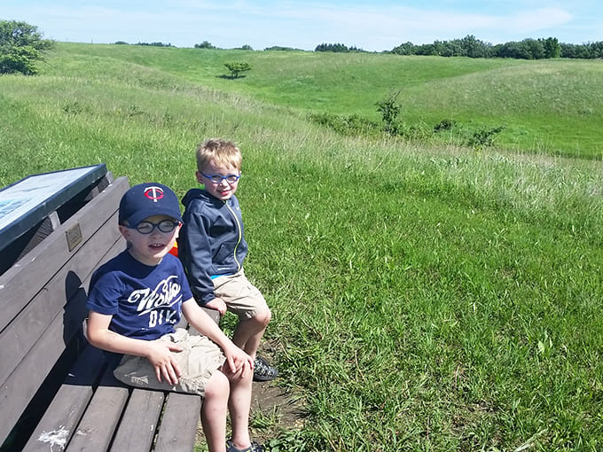 Young adventurers perch on a bench overlooking prairie vistas, proving that sometimes the best entertainment doesn't require batteries or Wi-Fi.