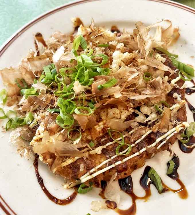 The legendary Okonomiyaki arrives like an edible work of art &ndash; a savory Japanese pancake topped with bonito flakes that dance as if performing just for you.