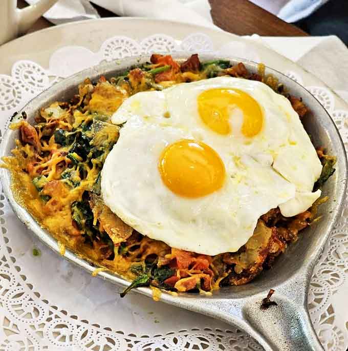 The Popeye breakfast skillet arrives loaded with spinach and eggs, making you feel healthy while absolutely indulging.